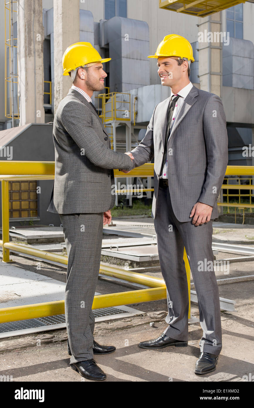 Full length of two architects greeting on construction site Stock Photo ...
