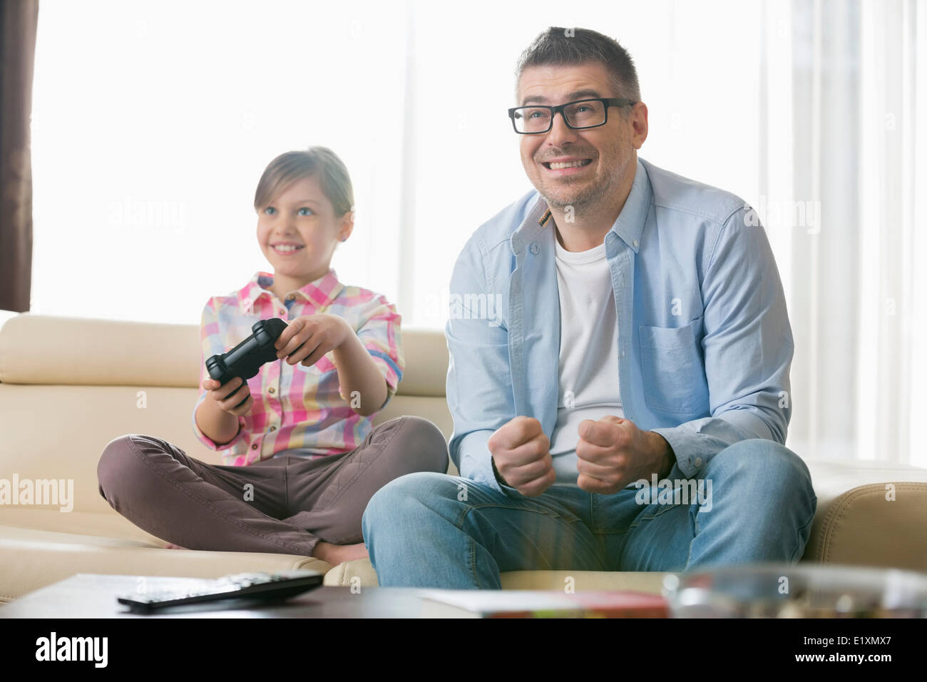 Happy father and daughter enjoying video game in living room Stock ...