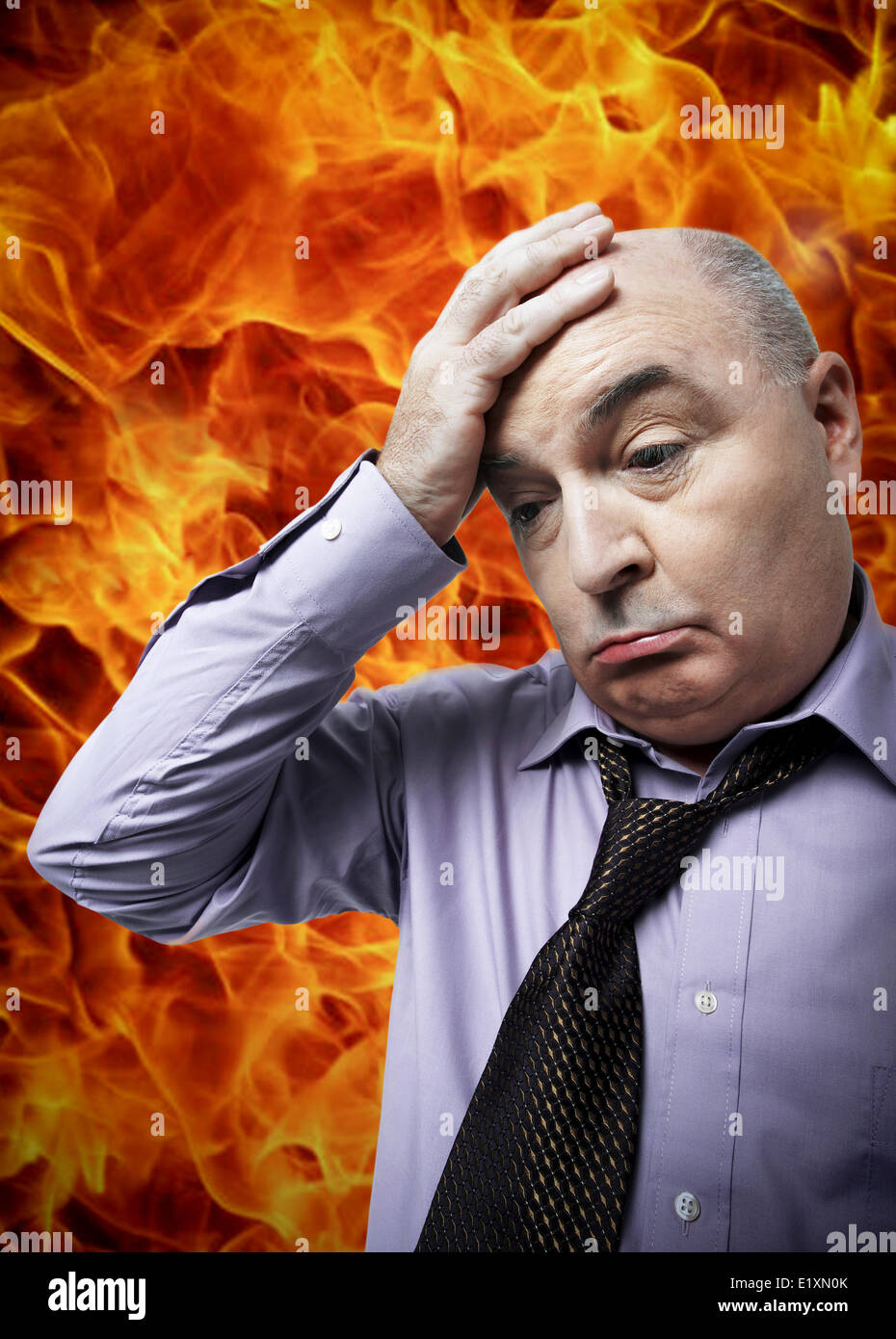 Frustrated businessman with hand on head standing against fire Stock ...