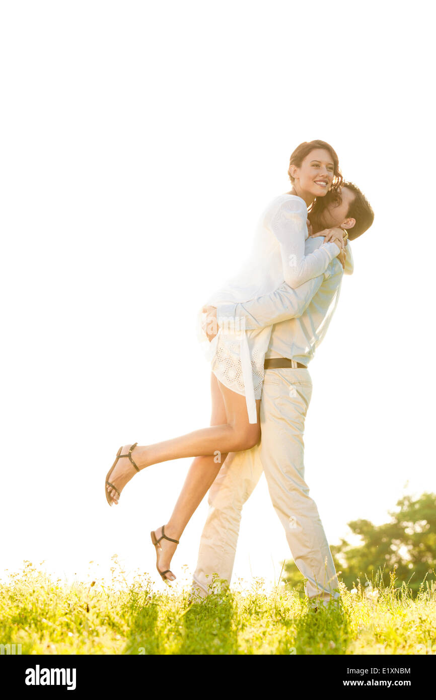 Side view of man lifting woman in park against clear sky Stock Photo ...