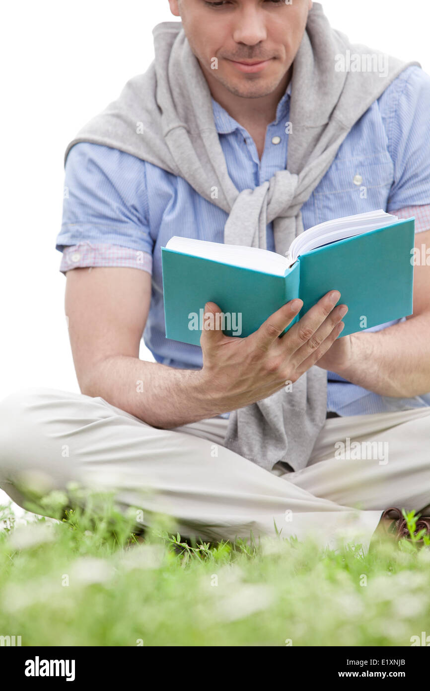 Low section of young man reading book on grass Stock Photo - Alamy