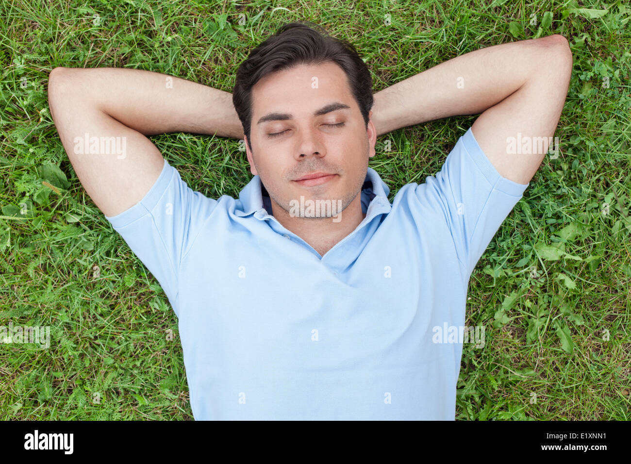Young man with hands behind head lying on grass Stock Photo - Alamy