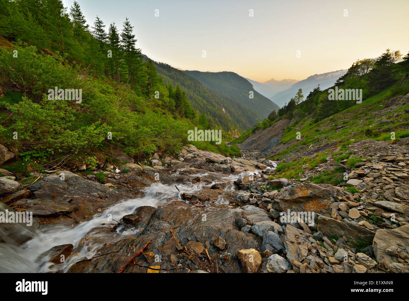 Mountain stream flowing on very steep eroded rocky slopes at sunset in ...