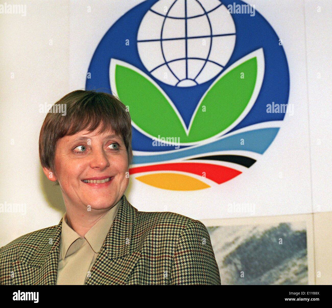 Federal environment minister Angela Merkel stands next to the logo of ...