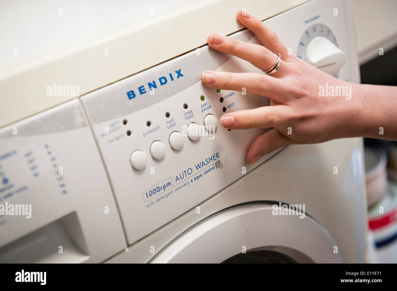 A young woman university college student using the washing machine to ...