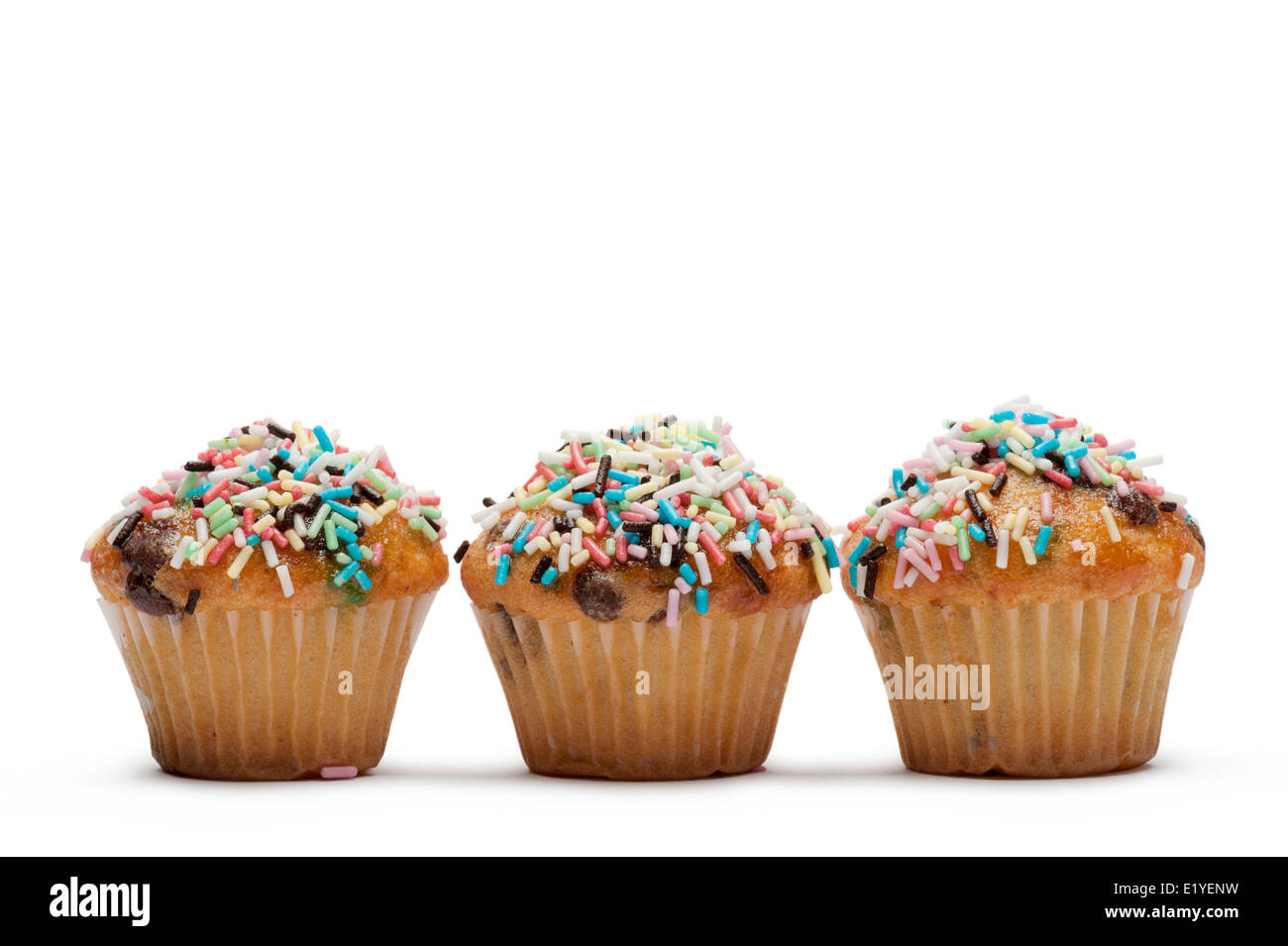 three little muffins with colorful chocolate sprinkles on white ...