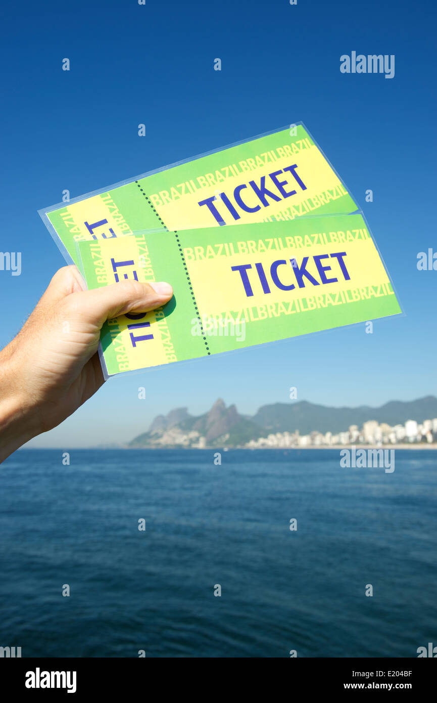 Hand holding pair of Brazil tickets in front of sea view Ipanema Beach ...