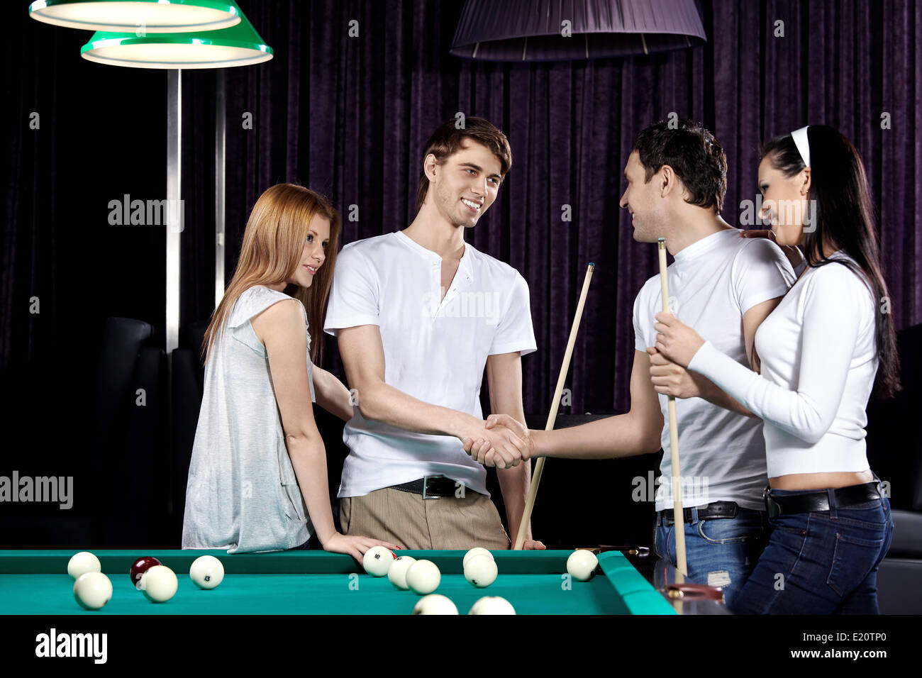 Young people with cue at a billiard table Stock Photo - Alamy