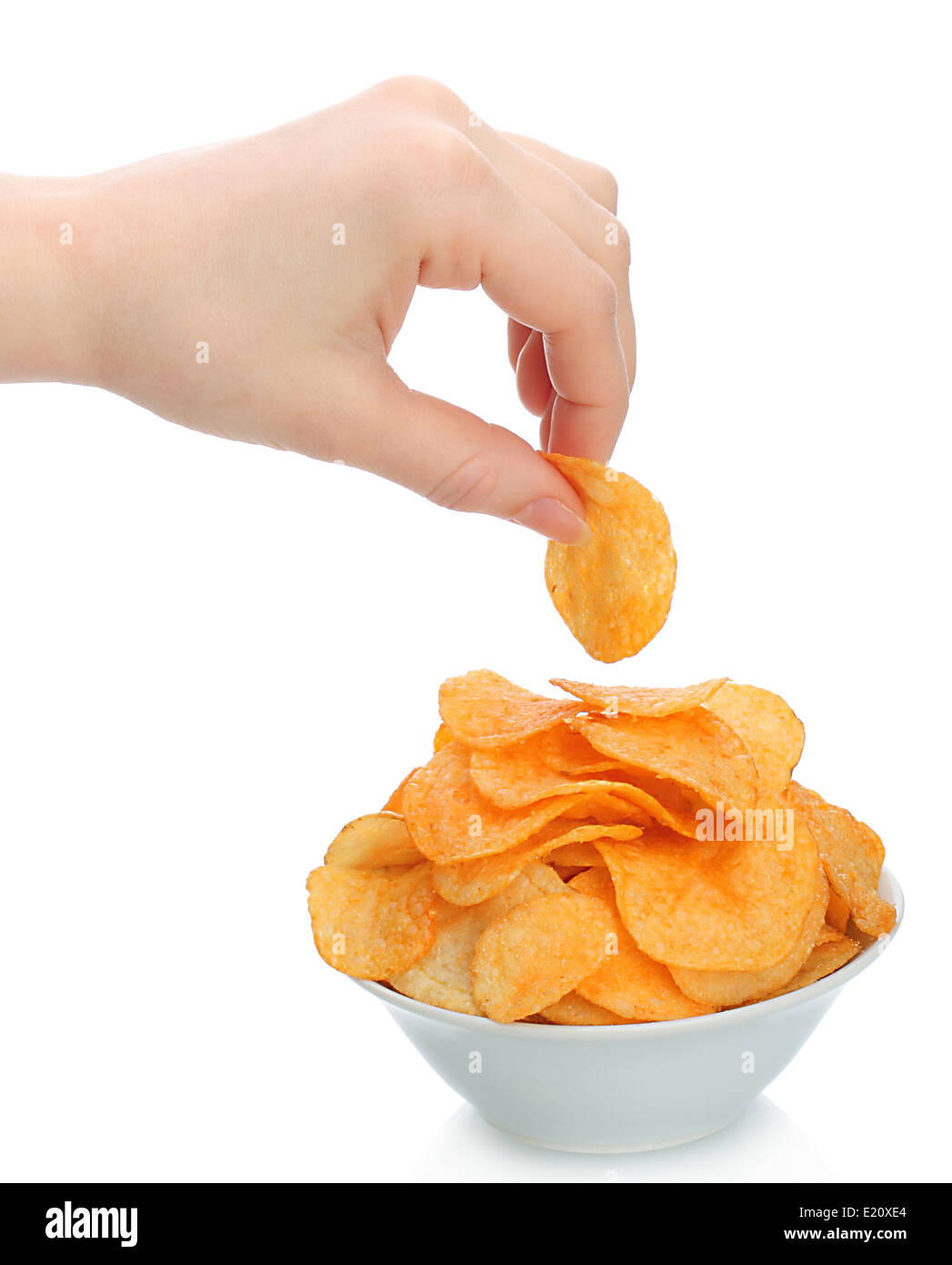 Hand holds a potato chip with the bowl of potato chips on white ...