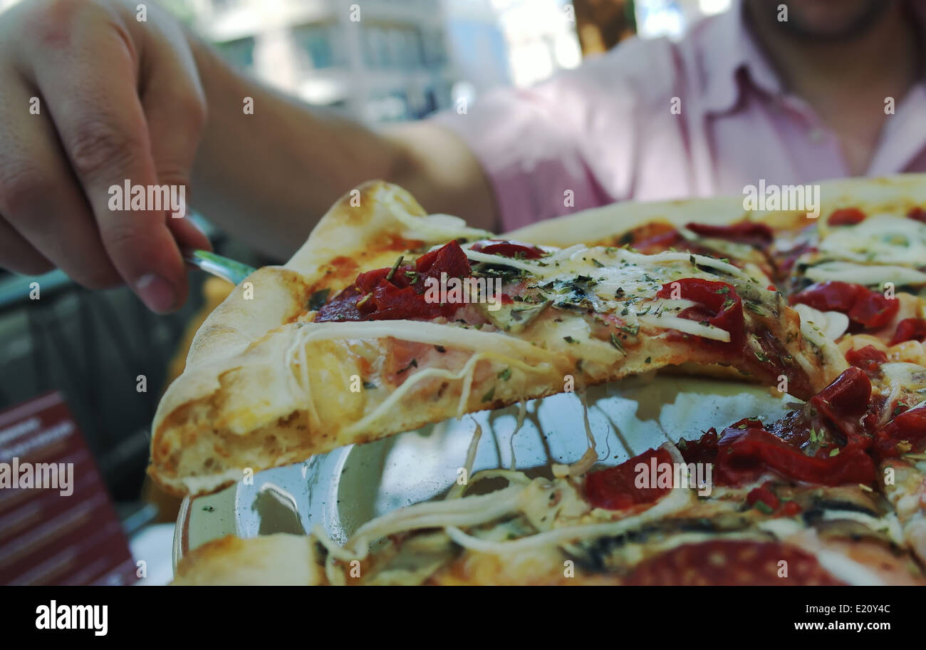 Pizza and slice of pizza in hand Stock Photo - Alamy