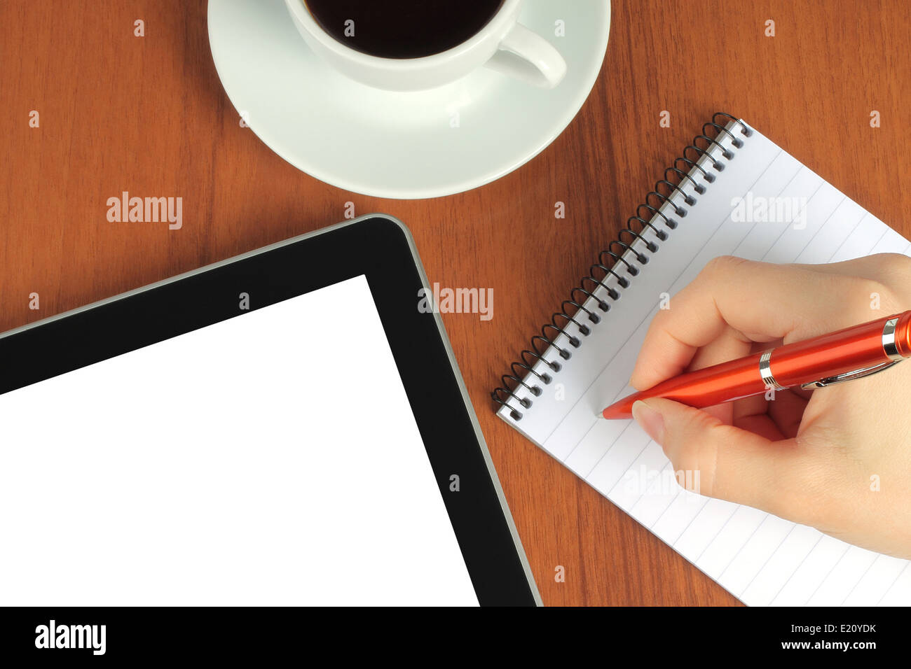 Touch screen device, notepad, writing hand and cup of coffee on wooden ...