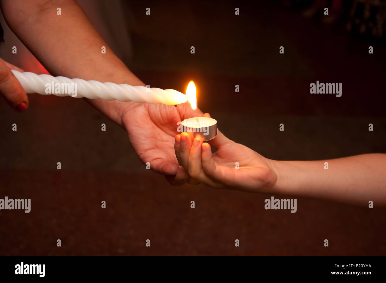 Two hands lit candles Stock Photo - Alamy