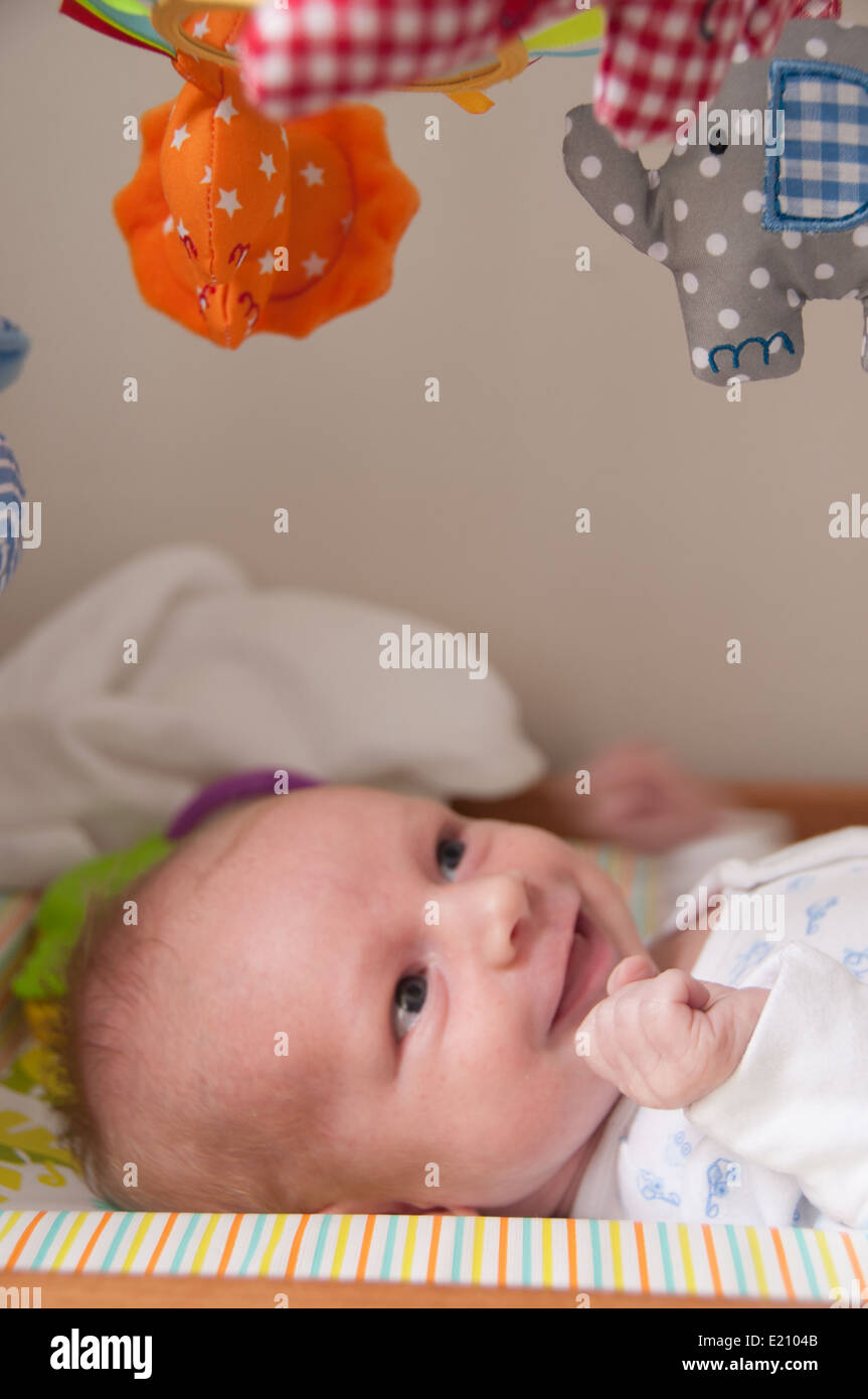 Newborn baby looking up and smiling at mobile toy Stock Photo - Alamy