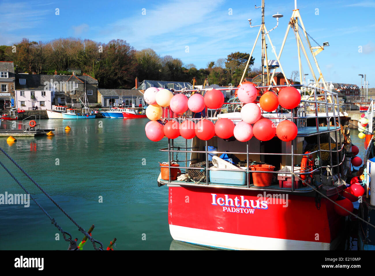 A red fishing boat with red floats in harbour with blue water and blue ...