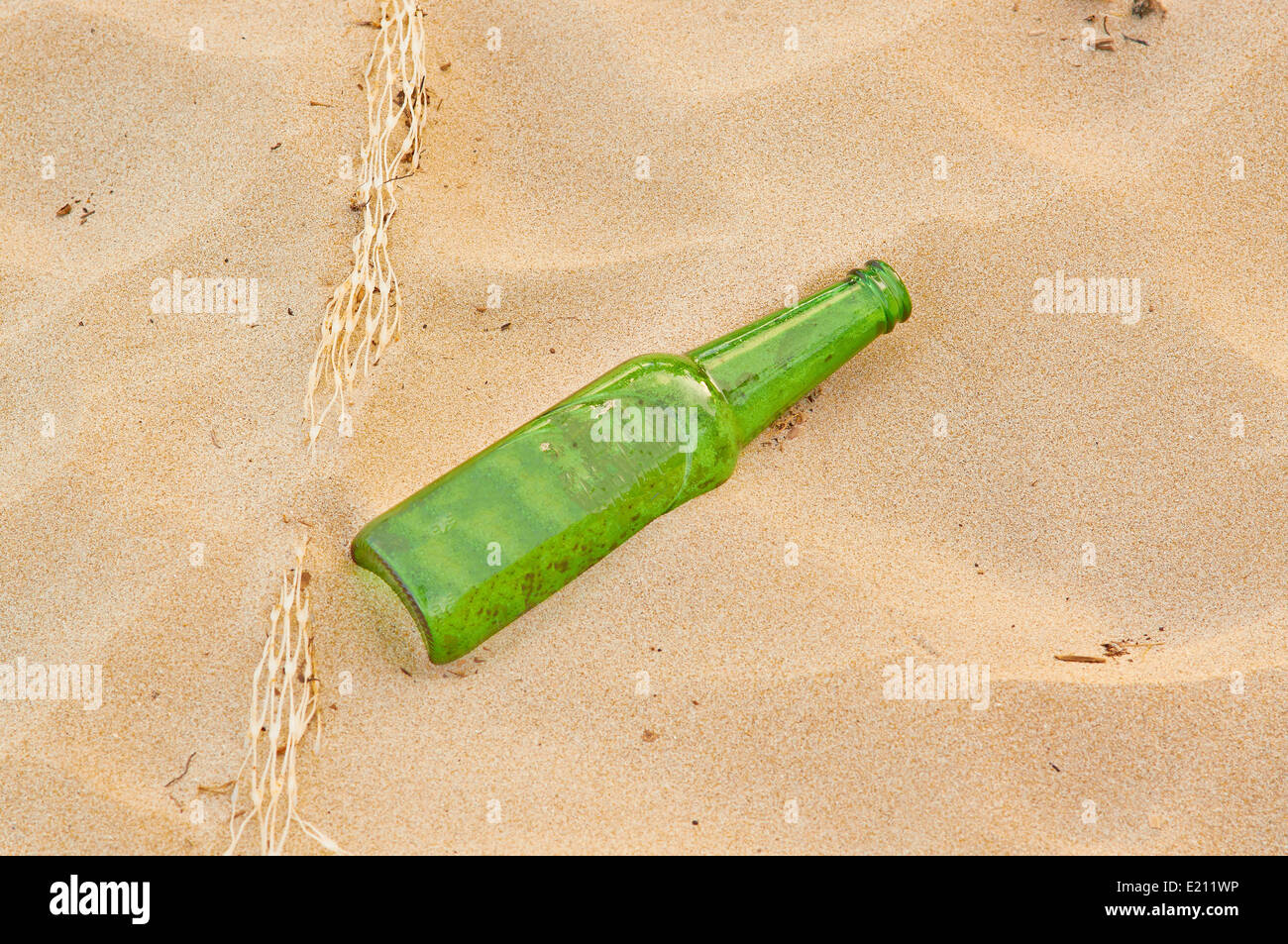 Empty green beer bottle on beach Stock Photo - Alamy