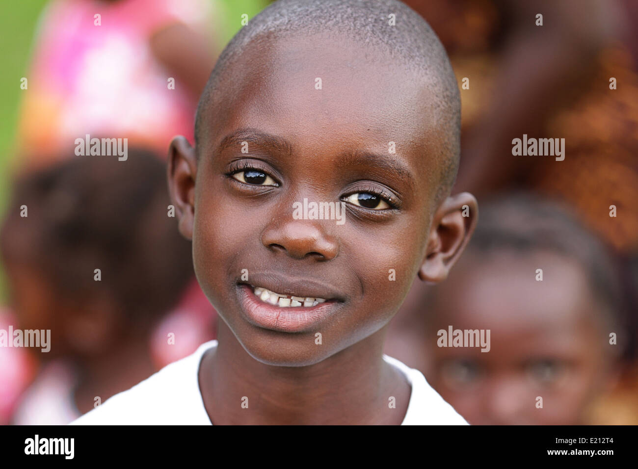 A smiling Zambian orphan boy stands out from faces in the background ...
