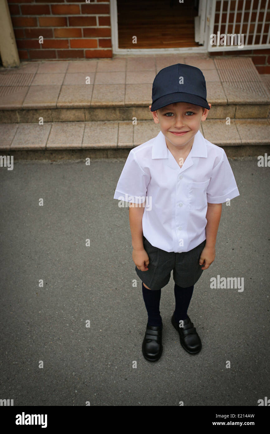 A young schoolboy in school uniform smiling on his first day of school ...