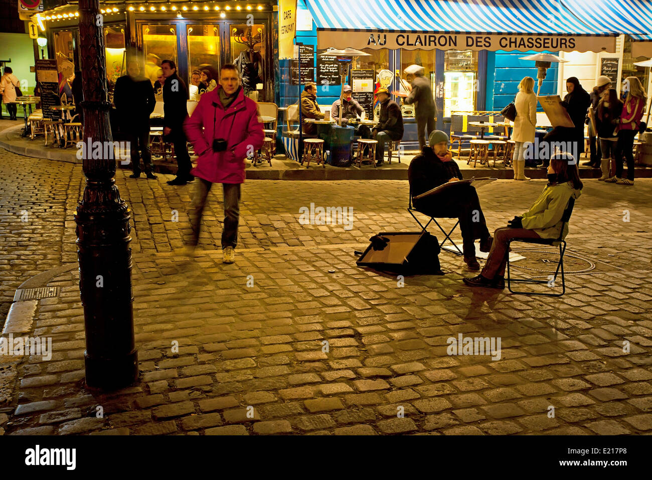 A man draws a portrait of a young passerby in a typical night scene of ...
