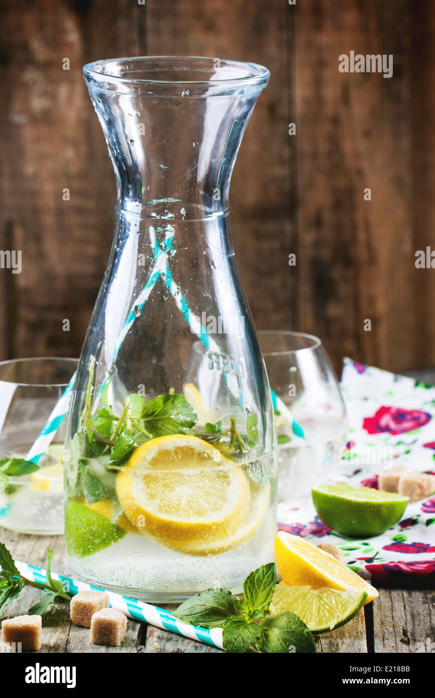Glass pitcher of homemade lemonade with lemon, lime, sugar and mint on ...