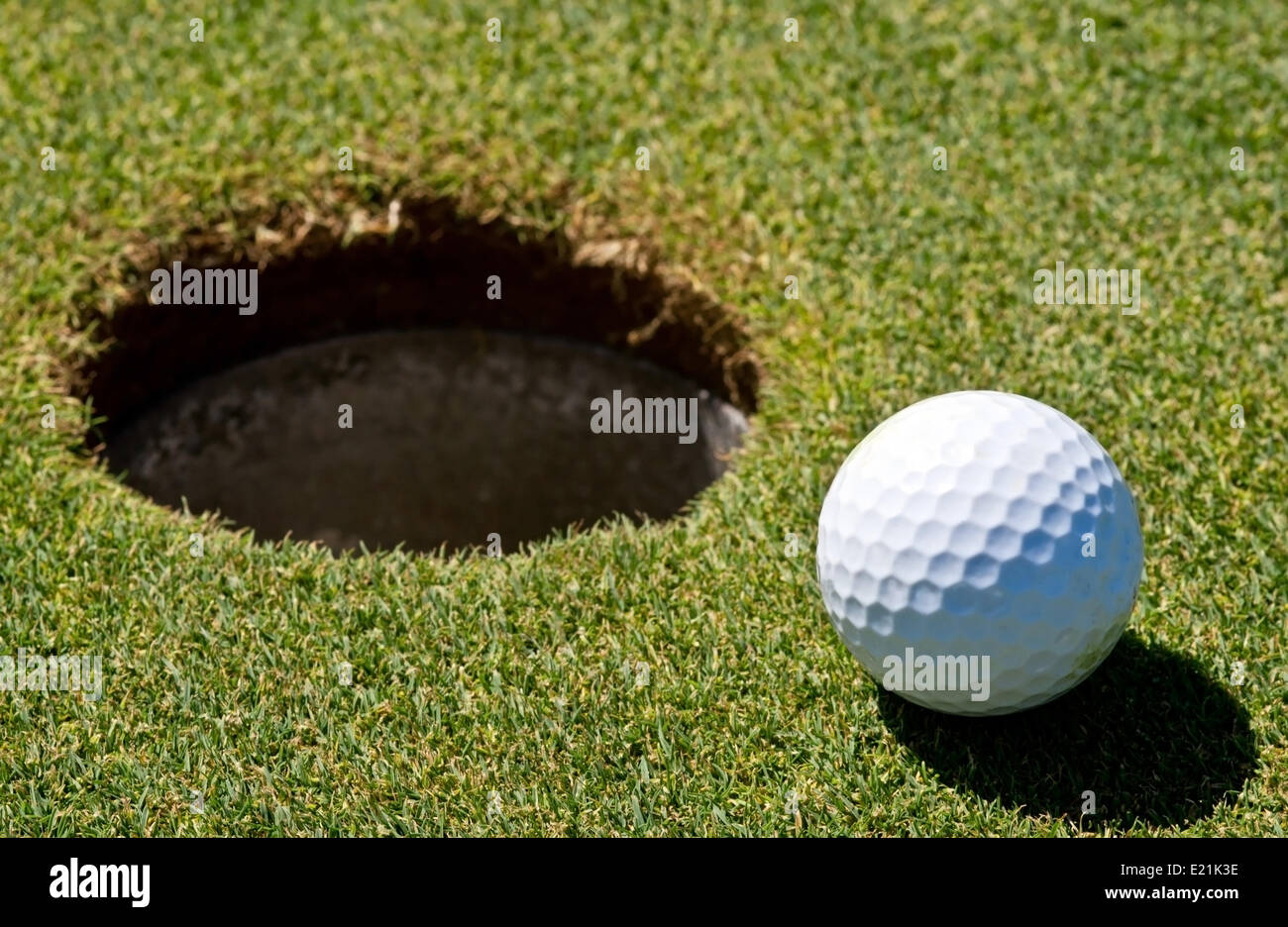 Golf ball next to a hole Stock Photo - Alamy