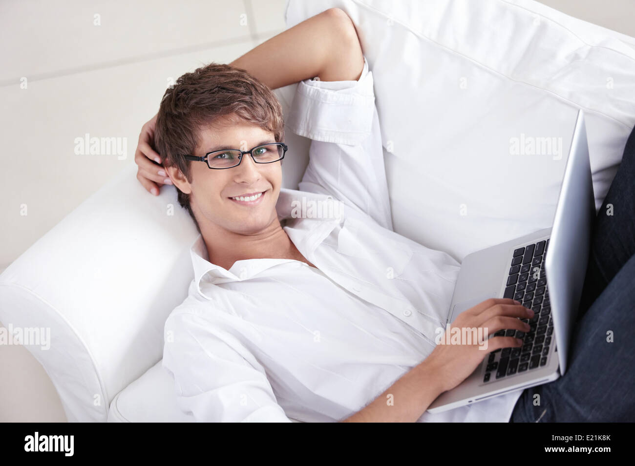 Attractive man with laptop on a couch Stock Photo - Alamy