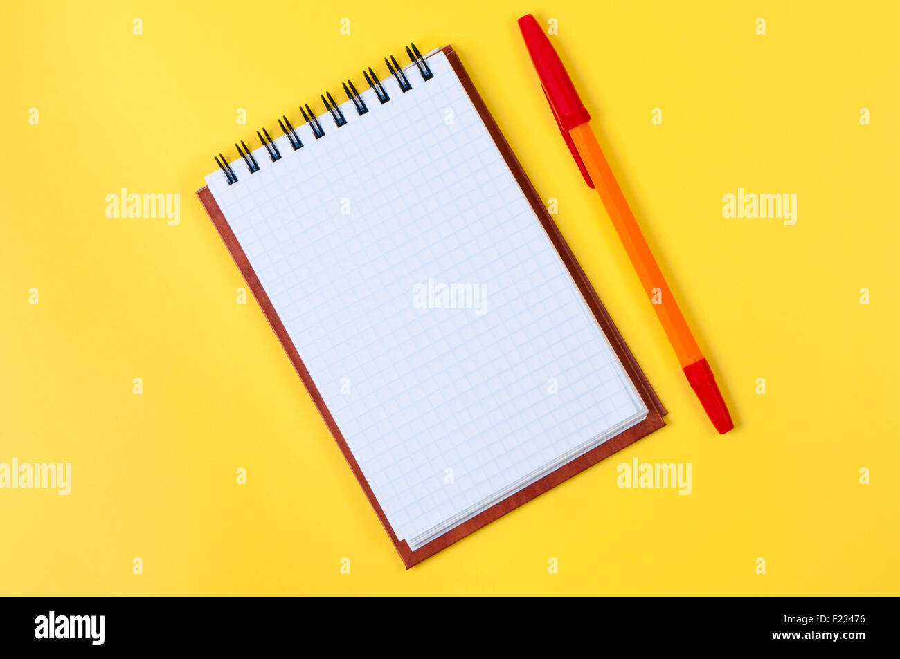 Notepad and pen on yellow background Stock Photo - Alamy