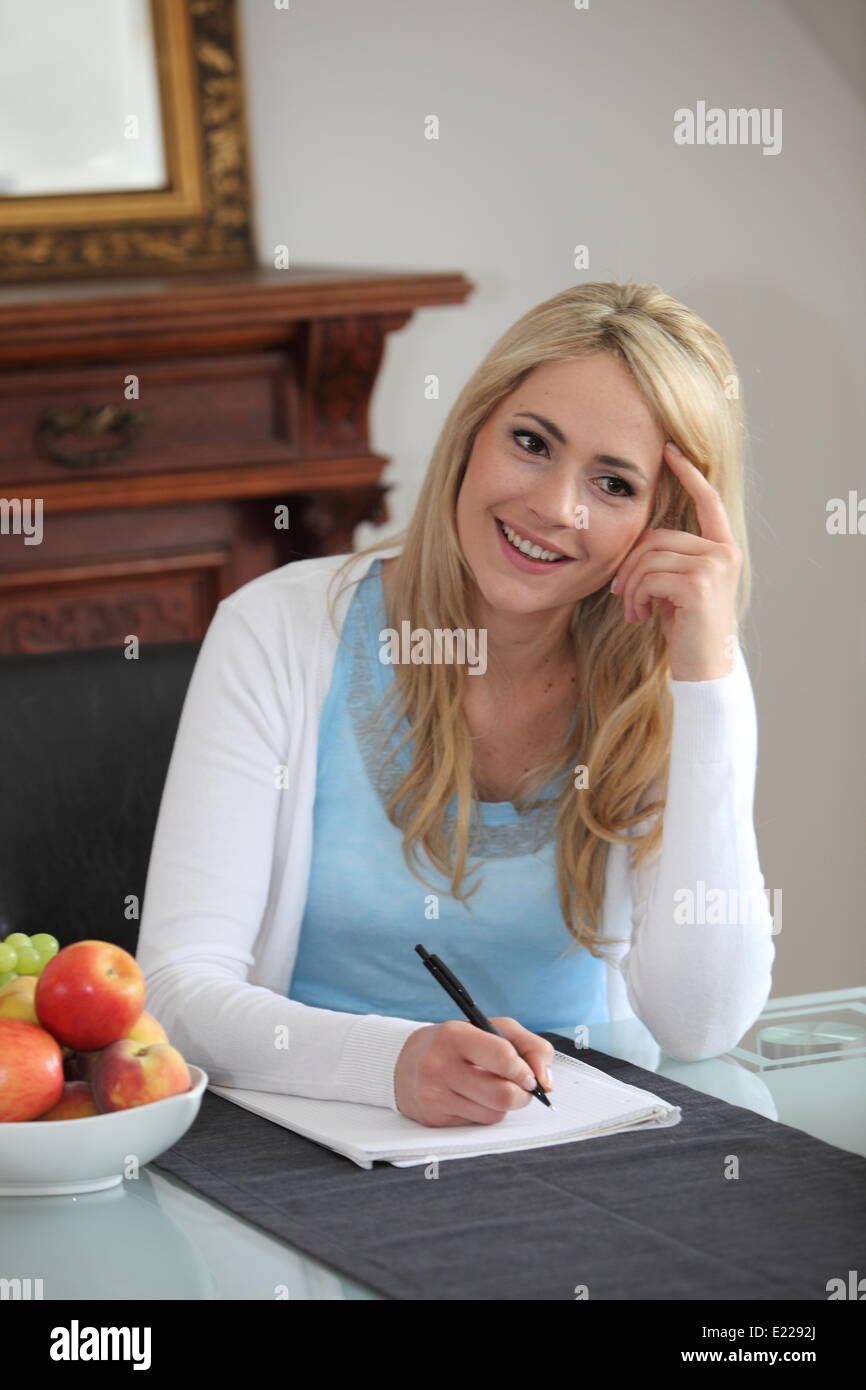 Woman thinking as she writes correspondence Stock Photo - Alamy