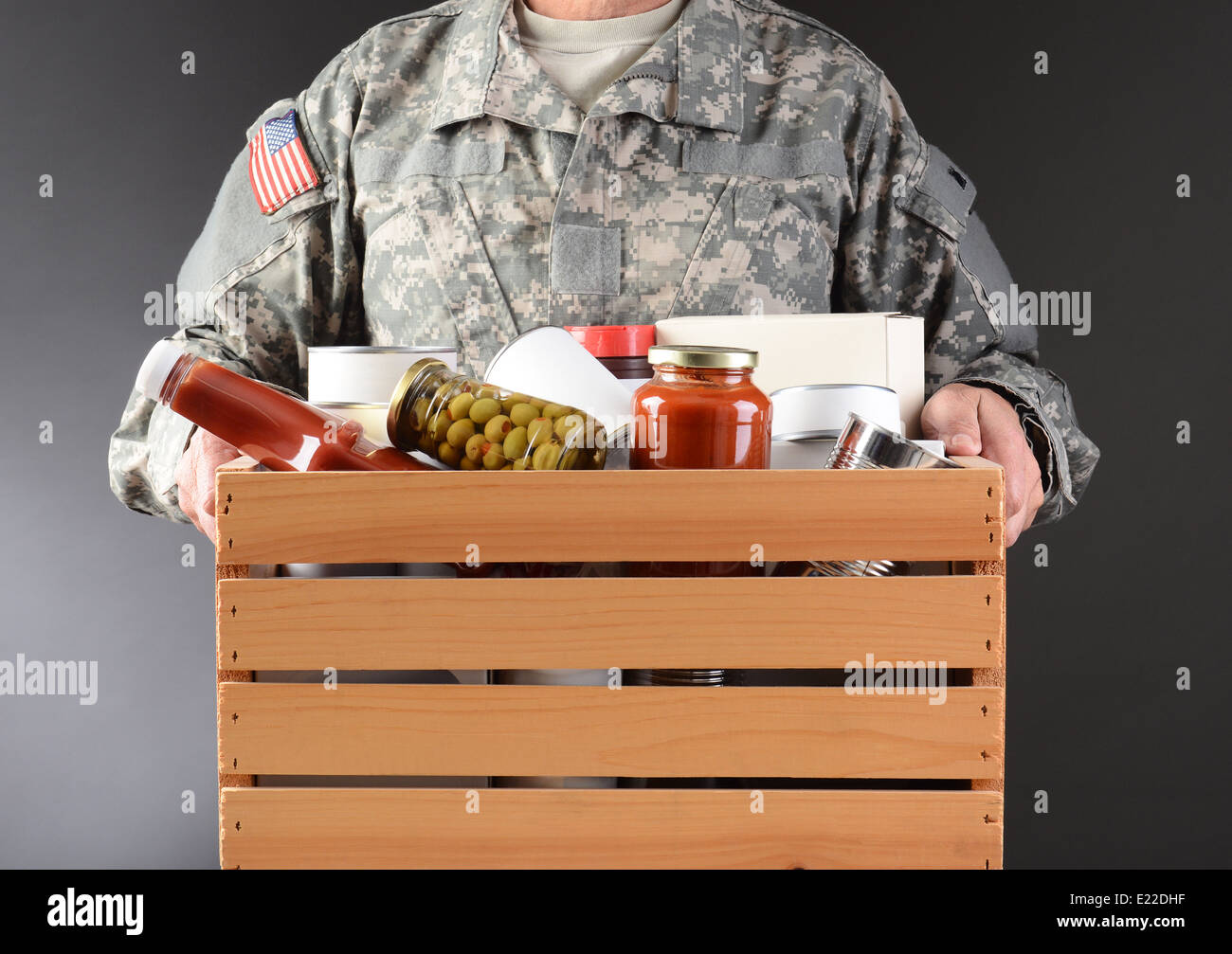 Closeup of a soldier in fatigues holding a wooden box full of canned ...