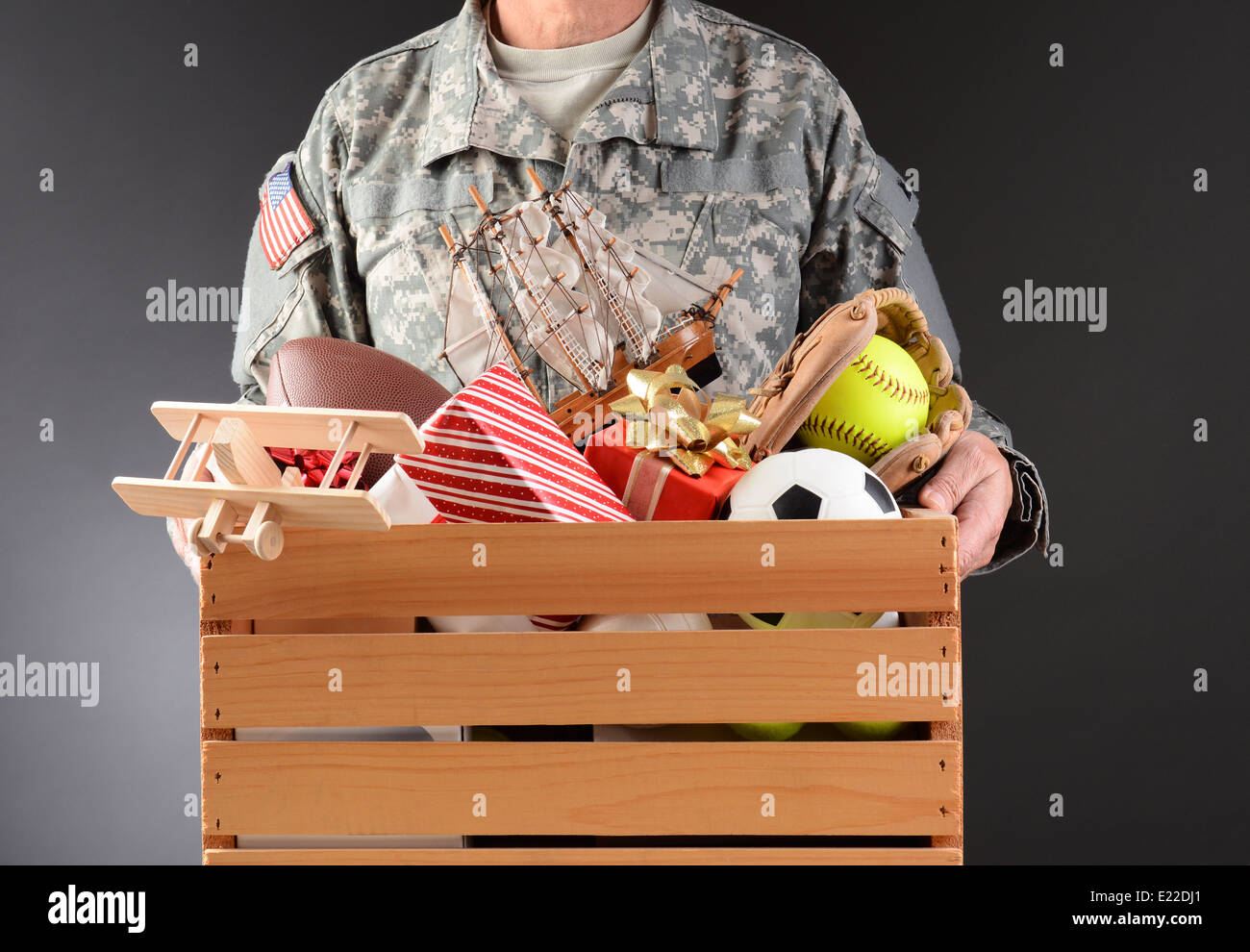 Closeup of a soldier in fatigues holding a wooden box full of toys and ...
