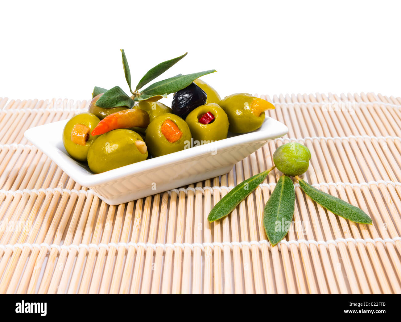 stuffed olives with olive branch and leaves on a rustic mat background ...