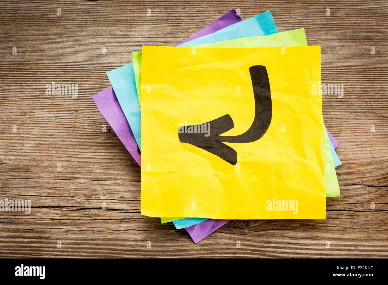 black arrow on a yellow sticky note against grained wood Stock Photo ...