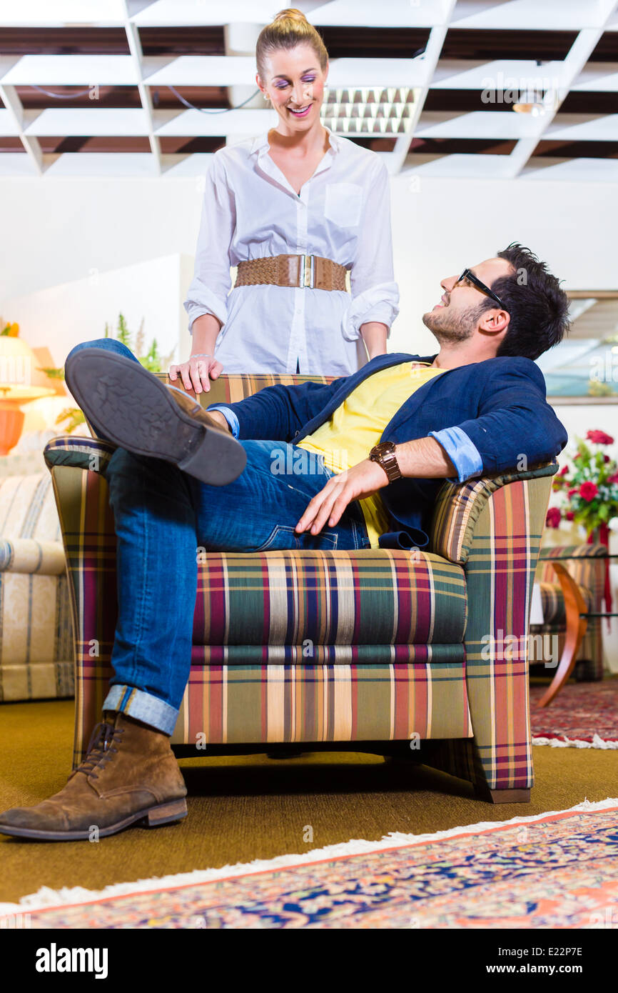 Young couple selecting together armchair in furniture store Stock Photo ...