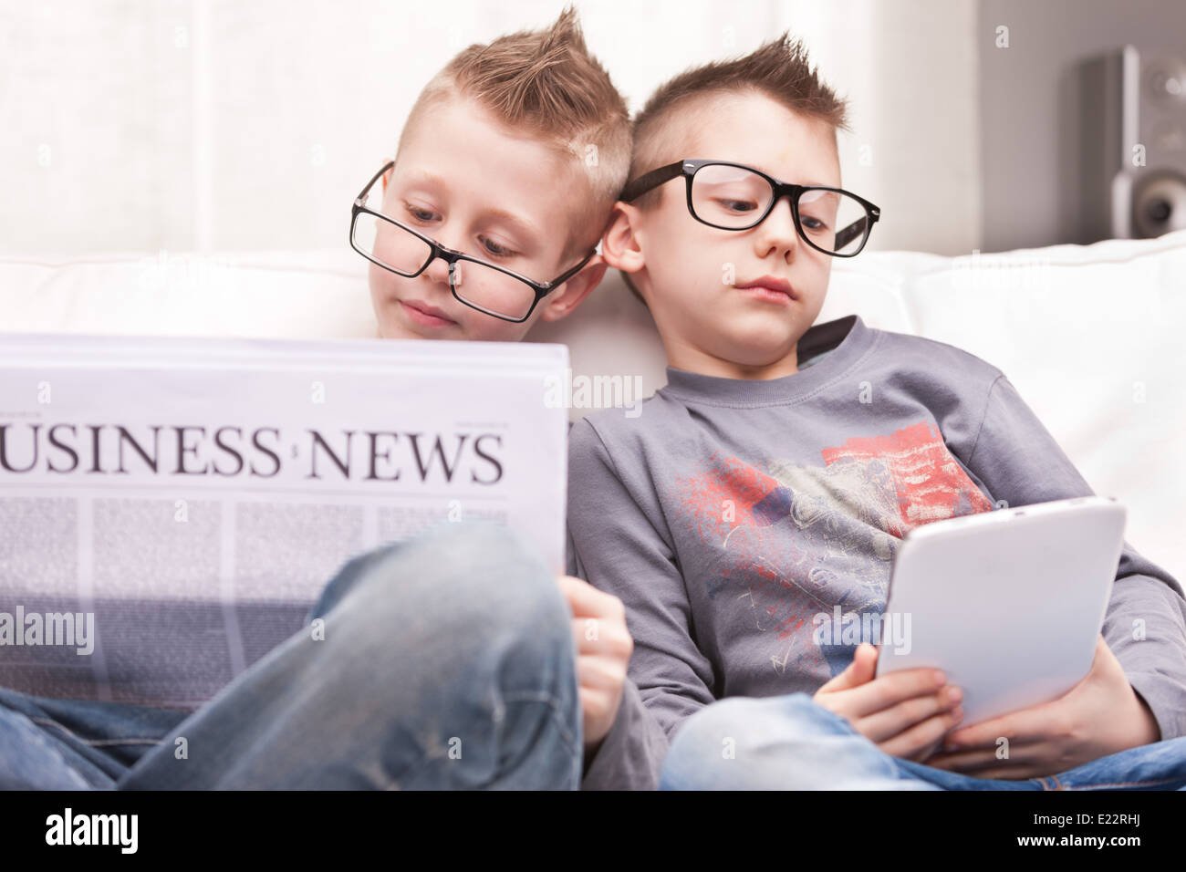 two little boys reading on newspapers or digital devices Stock Photo ...