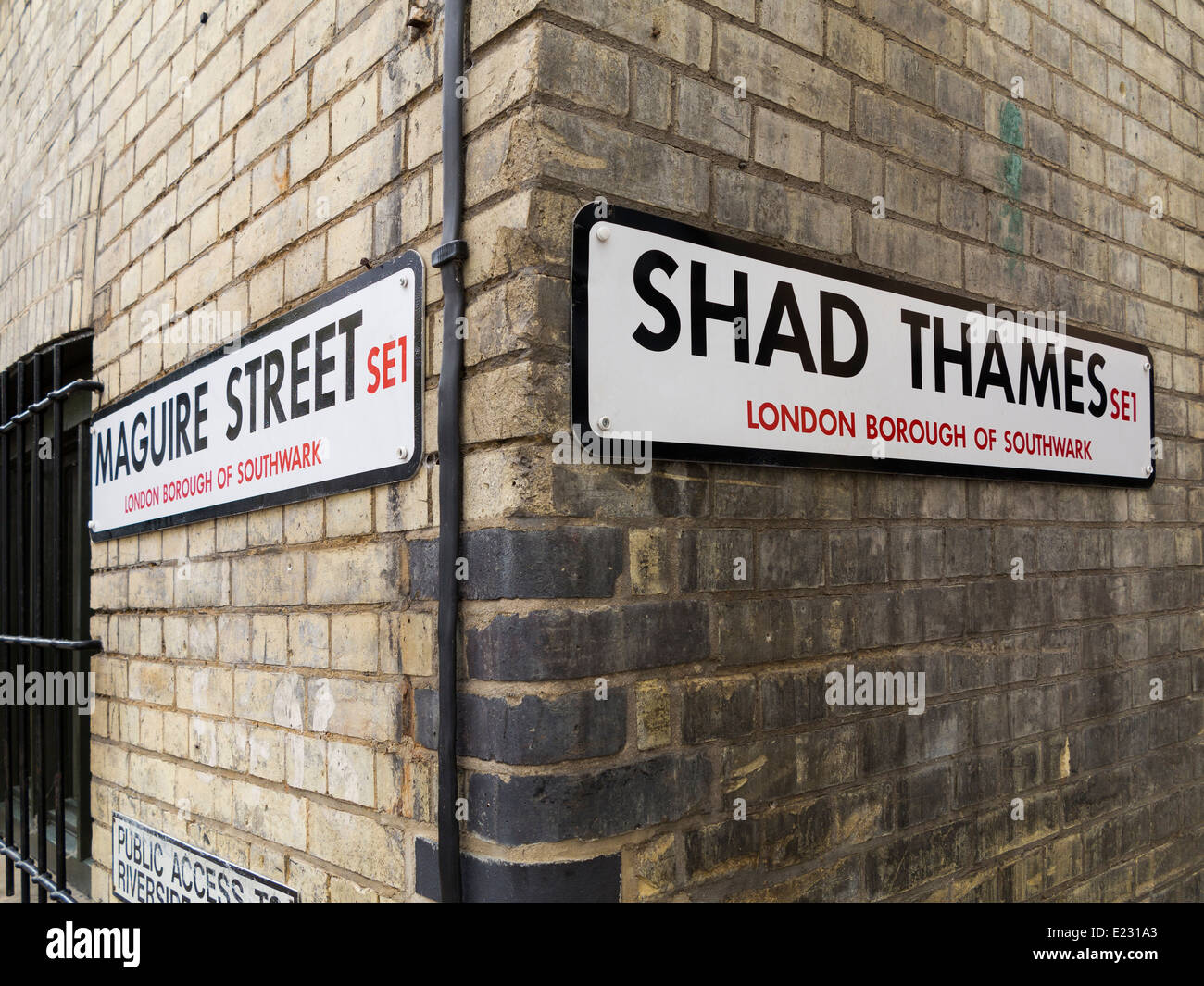 Shad Thames and Maguire Street SE 1 road signs on the corner of a brick ...