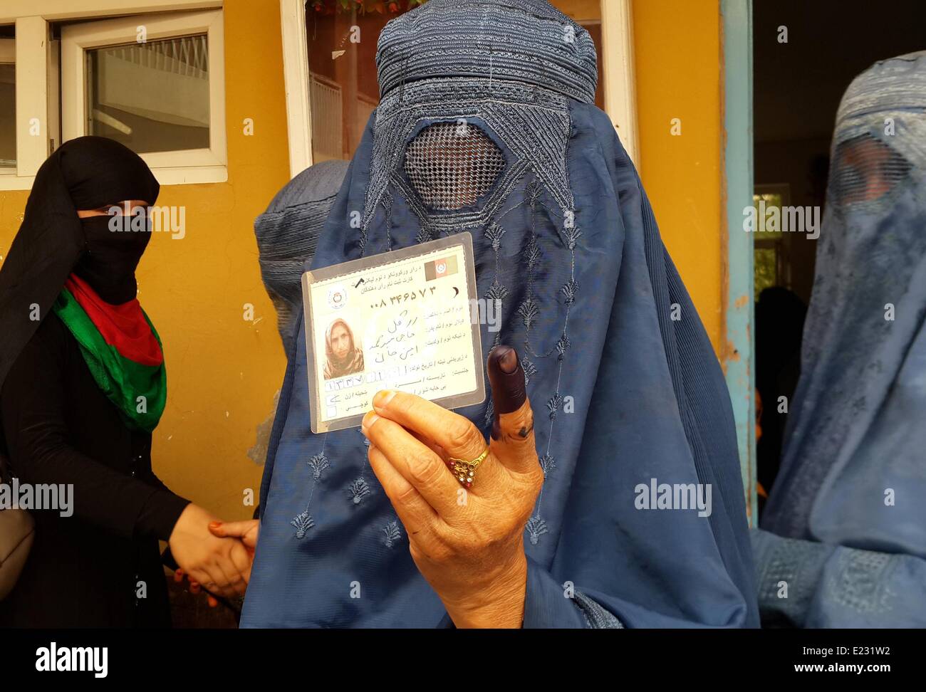 An Afghan women in traditional burqa show her voting card and inked ...