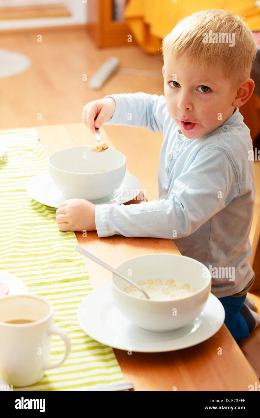 Happy childhood. Blond boy kid child eating corn flakes cereal with ...