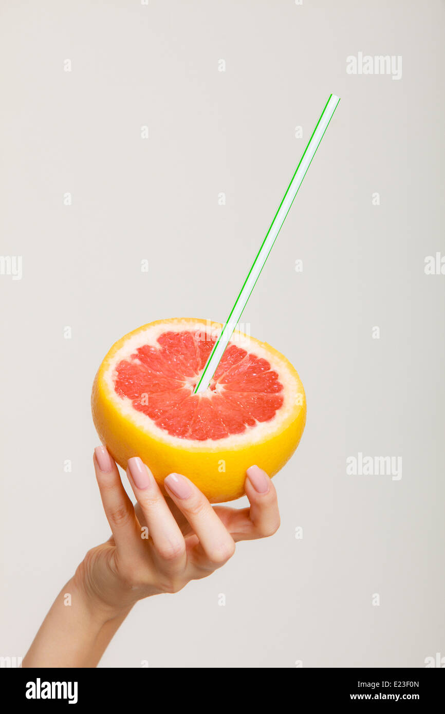 Summer vacation. Grapefruit citrus fruit with drinking straw in female ...