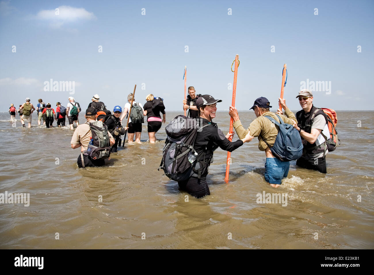 Guides helping people crossing deeper water during a hiking trip called ...