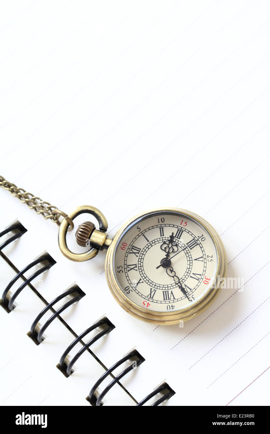 Pocket watch laying on a white notebook page Stock Photo - Alamy