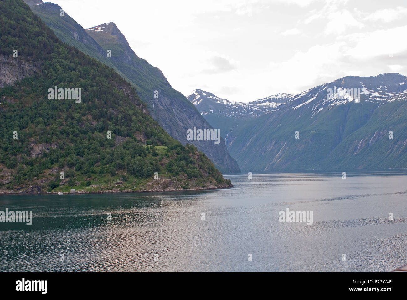 CruIsing down the Geiranger Fjord in Norway with snow capped mountains ...
