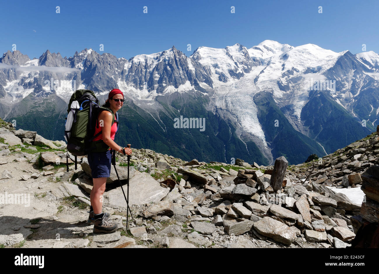 A lady trekker with a full rucksack and Mont Blanc in the French Alps ...