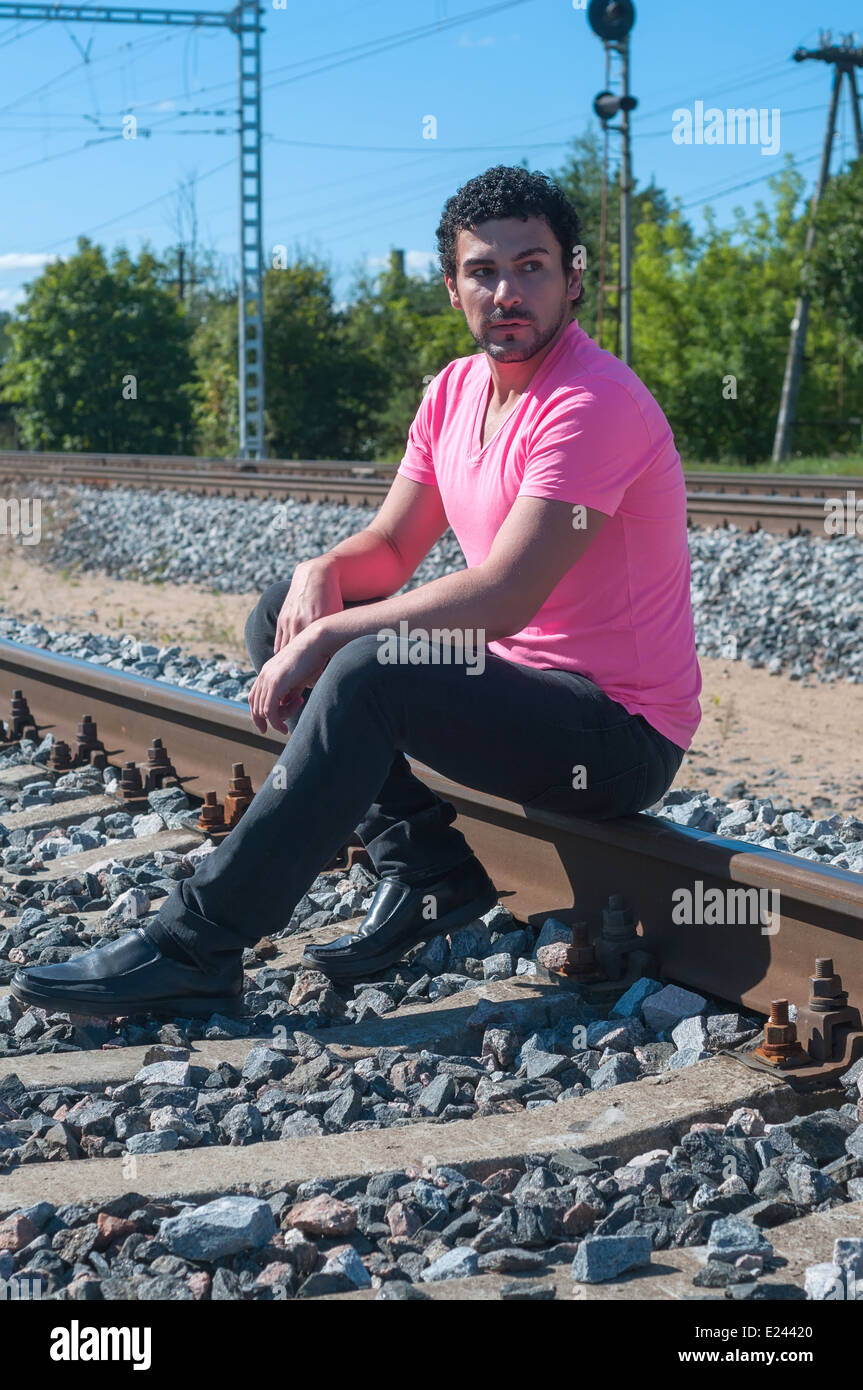 Young man sitting on the rail track Stock Photo - Alamy