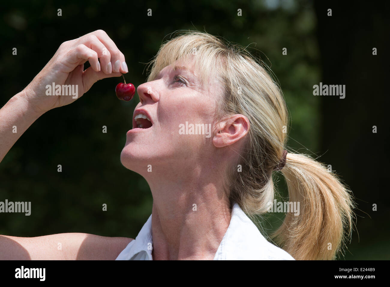 Woman eating cherries Stock Photo - Alamy