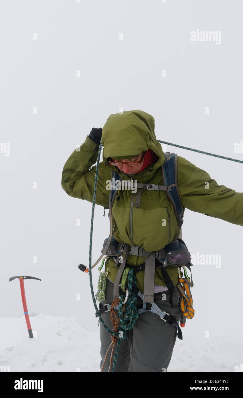A lady mountaineer coiling rope around her neck on the summit of the ...