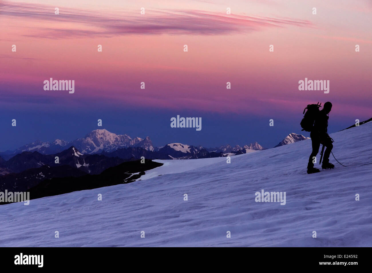 A climber starts the day in the Swiss Alps at dawn, with Mont Blanc on ...