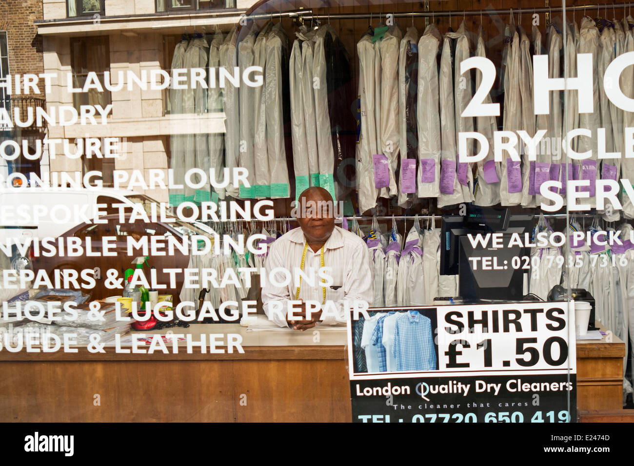 A cheerful businessman stands behind the counter of his dry cleaning ...