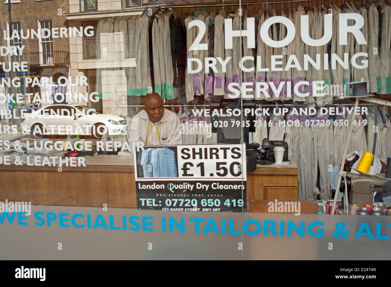 A pensive businessman stands behind the counter of his dry cleaning ...