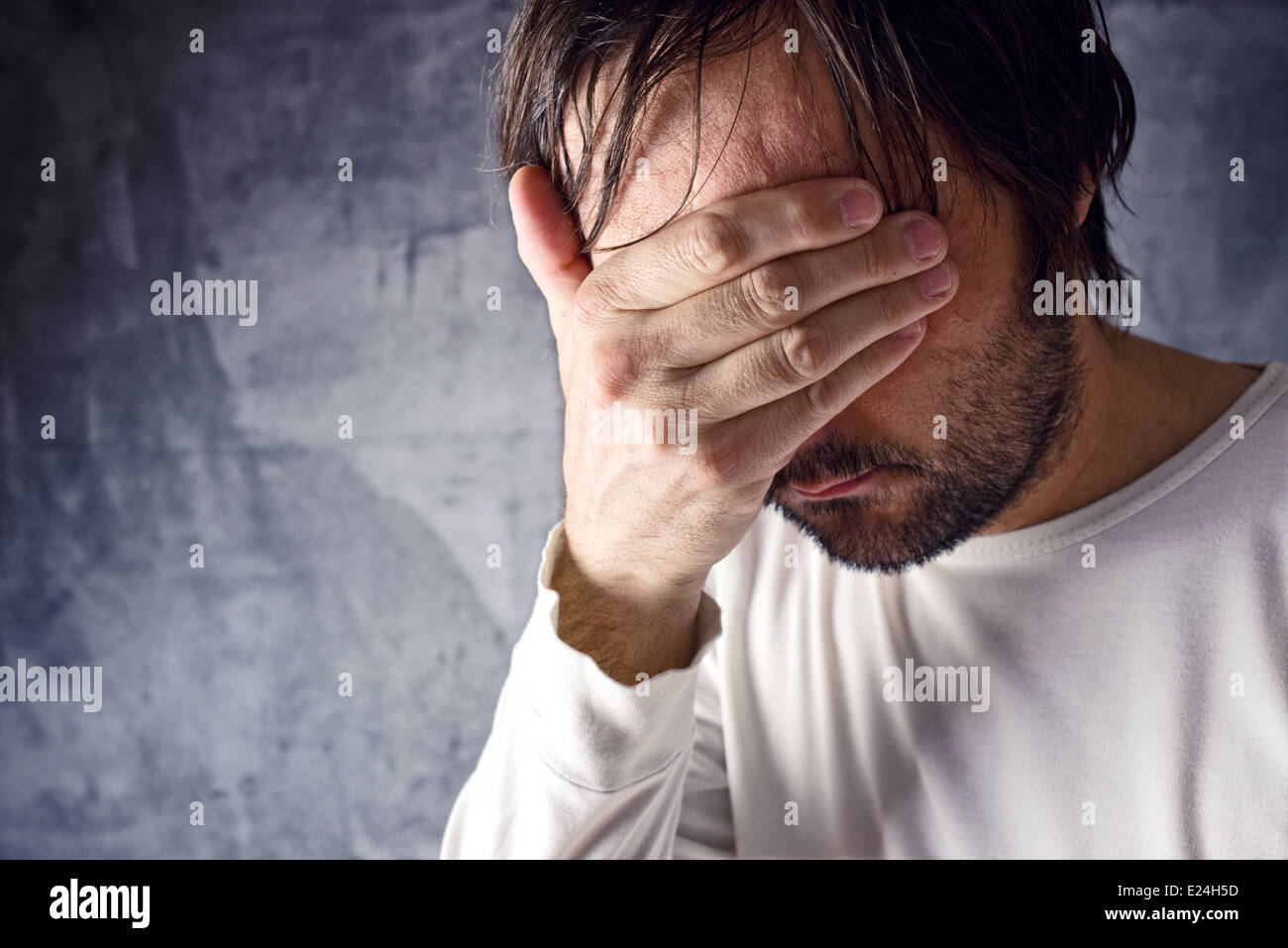 Depressive man crying with hand covering his face, looking upset and ...