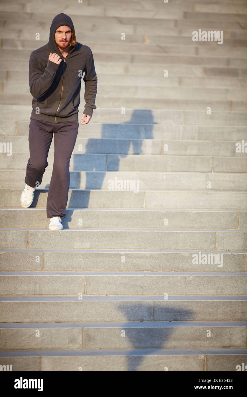 Portrait of young attractive sportsman running down steps Stock Photo ...