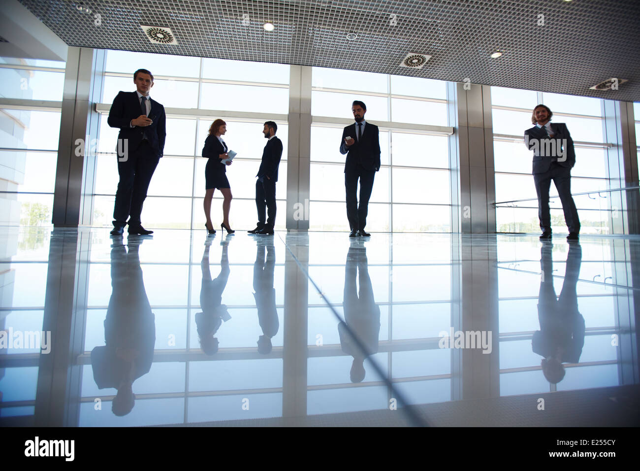 Silhouettes of several office workers standing by the window and ...